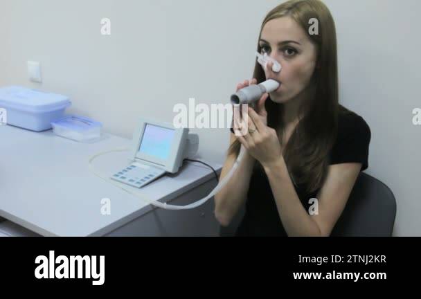 Girl breathes into a spirometer tube closed-toe to check the oxygen in ...