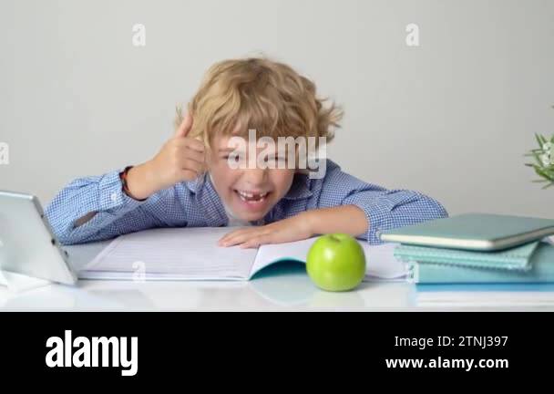 Elementary school student boy or girl writing letters, studying at desk ...