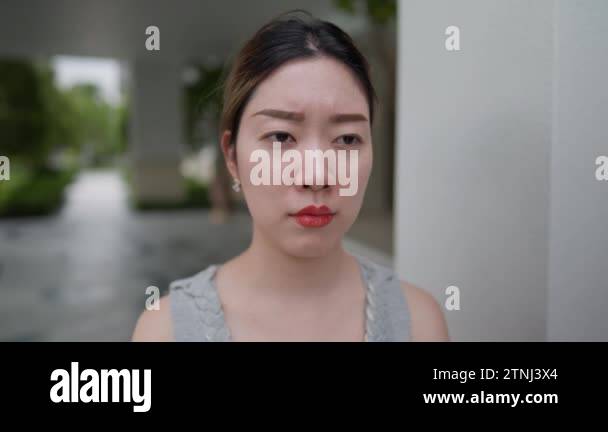 A close-up, a young Asian womans face reveals the weight of stress. Her ...
