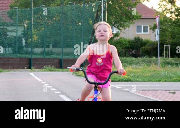 Girl rides the bike at playground traffic. Little girl on bike in the summer. Slow and revers ...