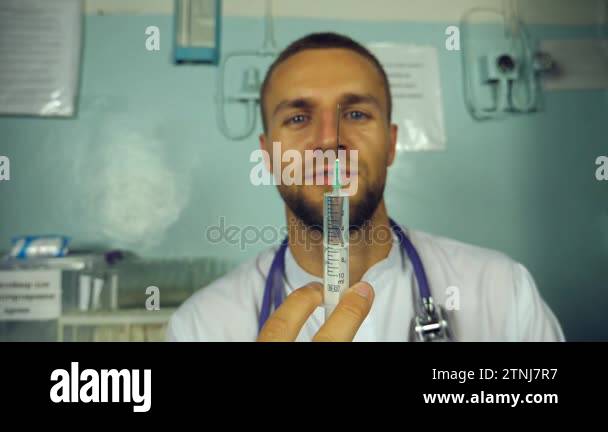 Portrait of young male caucasian doctor pouring a liquid from a syringe ...