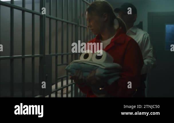 Prison officer leads female prisoner in orange uniform to prison cell ...