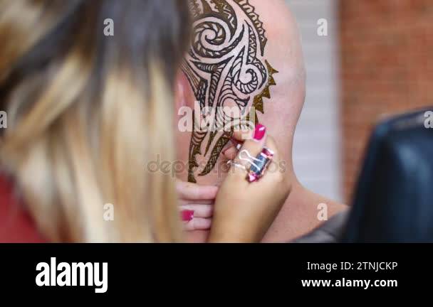 A girl, tattoo master, mehendi artist makes drawing of henna tattoo on ...