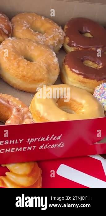 Large, open box of Tim Hortons donuts in contrasted light, with variety ...