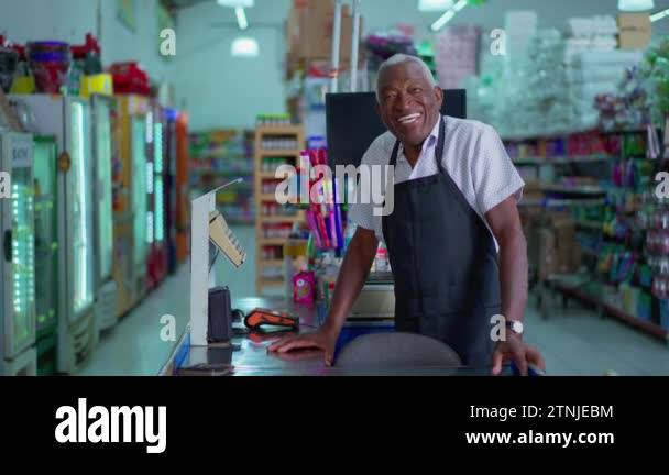 One happy black senior employee standing at supermarket cashier smiling ...