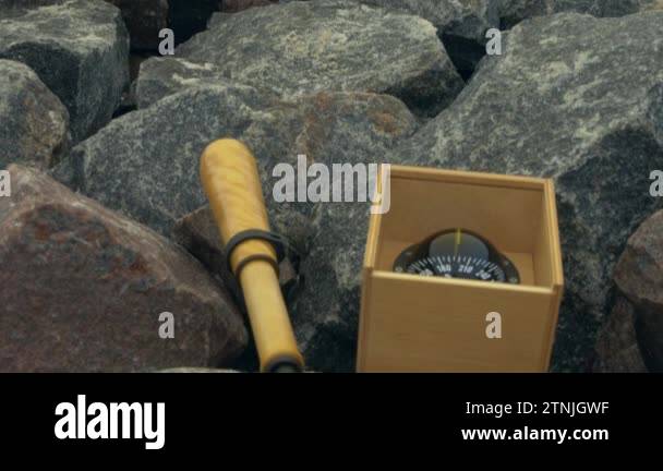 Compass and telescope spyglass on granite rocks. Metall pier, bollard ...