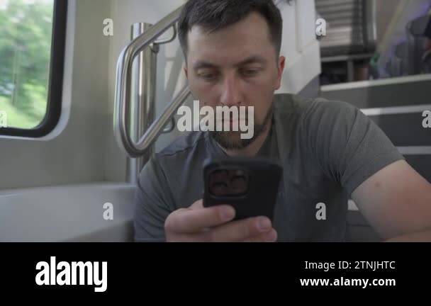 Male commutes in dual deck train seated on flyer and surfing internet ...