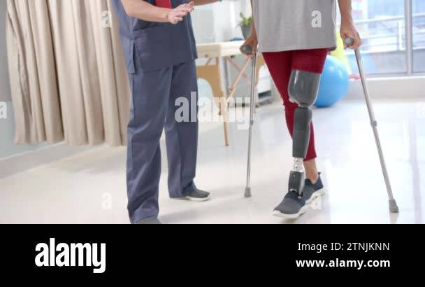 Caucasian female physiotherapist and female senior patient with prosthetic leg exercising ...