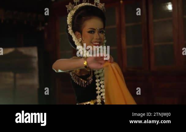 an Indonesian dancer smiles while wearing a traditional dress called a ...