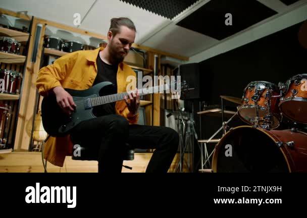 portrait of young rock artist with electric guitar in recording studio ...