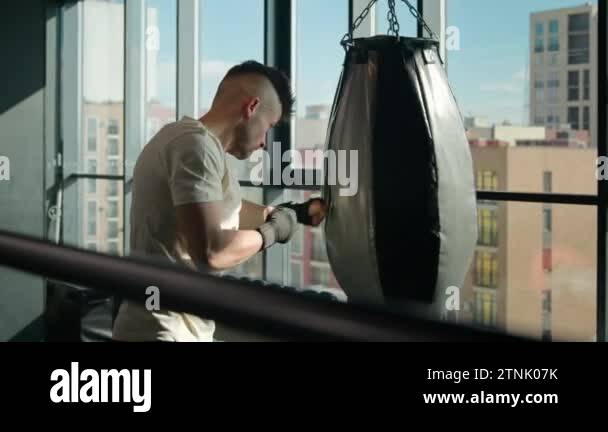 Active boxer sportsman in boxing gloves hitting punching bag intense ...