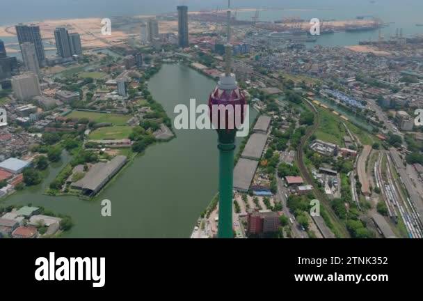 Fly around top of Colombo Lotus Tower on lake bank in city. People ...