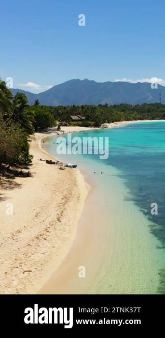 A tropical beach with palm trees and a blue ocean. Pagudpud, Ilocos ...