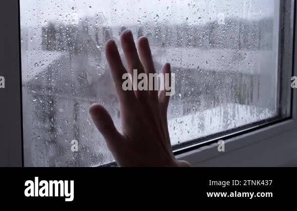 Woman Touches a Wet Misted Window with Hand. Fingers slide on wet glass ...