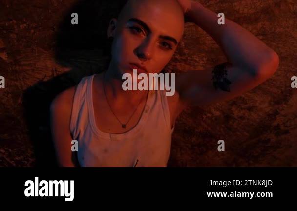 A woman with no hair on her head in a neon-lit basement is drawn behind ...