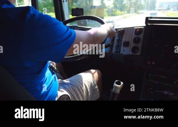 Unrecognizable lorry driver driving on city road at sunny day. Man ...