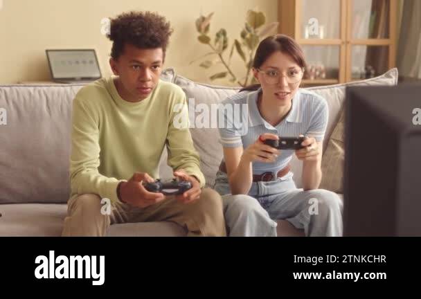 Two multiethnic gen z friends using controllers while playing video ...