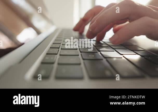 A woman focuses typing on a laptop, using the keyboard to work ...