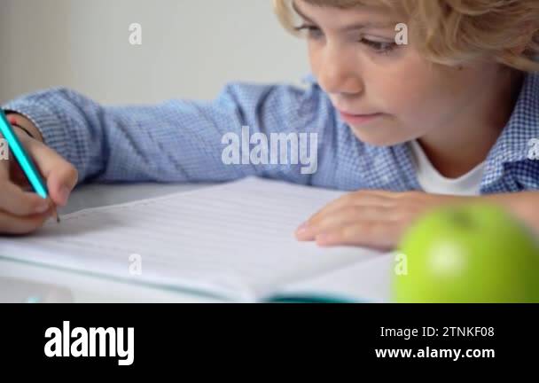 Elementary school student boy or girl writing letters, studying at desk ...