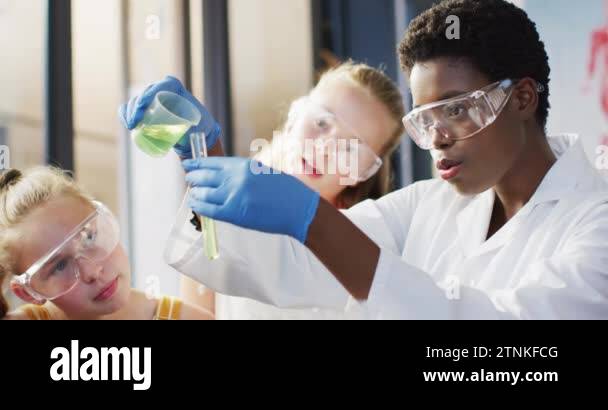 Diverse female teacher and happy schoolchildren having science class in ...