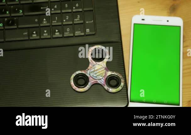 A toy spinner and smartphone with a green screen. Laptop and phone with ...
