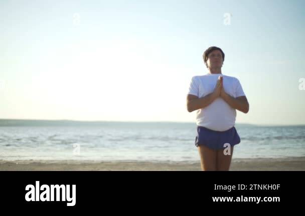 Man practice yoga asanas namaste at seaside sunrise rapid slow motion ...