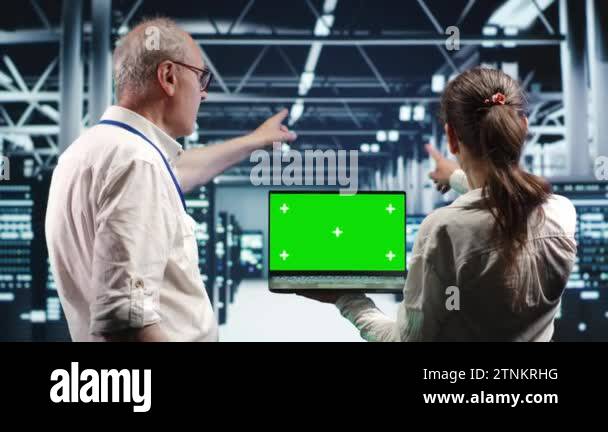 Admins using green screen laptop to monitor energy efficient data center clusters. Blade servers ...