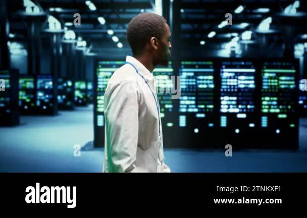 IT admin walking in server farm performing data backups and providing ...