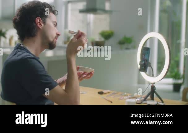 Medium shot of male beauty vlogger applying clay mask to face with ...