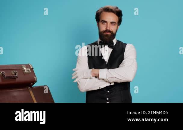 Experienced confident bellhop in studio, wearing formal hotel lobby ...