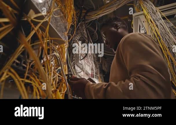 Low angle shot of Black male server room manager working on digital ...