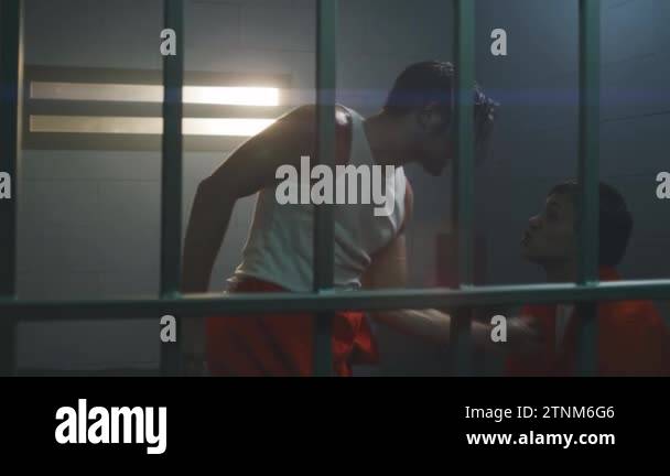Male prisoners fight in prison cell. Criminals in orange uniforms talk ...