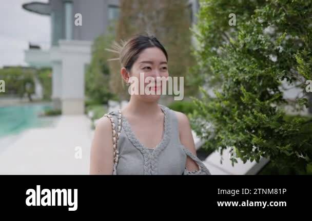 A young Asian woman lights up with a genuine smile as she looks ...