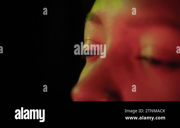 Close up of Woman eyes in Colorful Neon Light of TV television reflection. Pretty African ...