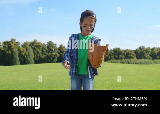 Cute preadolescent black boy pitcher wearing eye black and baseball cap ...