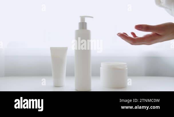 Finger push button on cream bottle in clean hand on white room ...