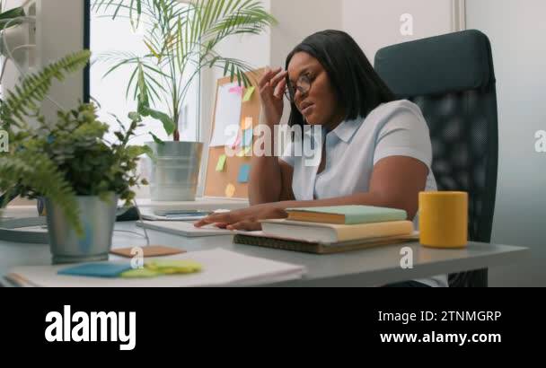 sick black woman sit at table work on laptop feels tired takes off ...