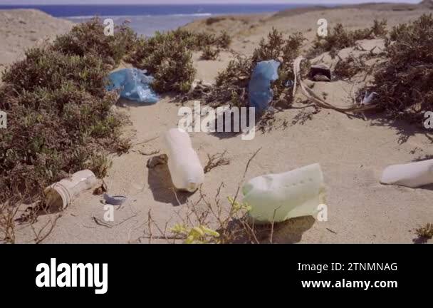 Plastic pollute of sandy desert with se in background, Closeup, Camer ...