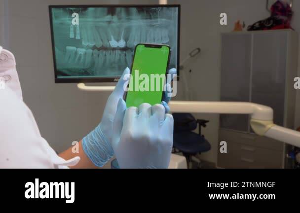 Closeup dentist hands sterile glove hold green screen cellphone at ...