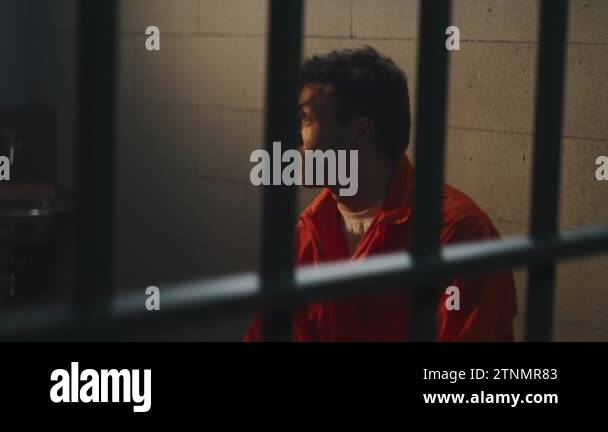 Prisoner in orange uniform sits in prison cell. Cellmate criminal ...