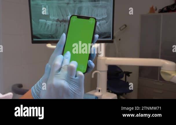 Closeup dentist hands sterile glove hold green screen cellphone at ...