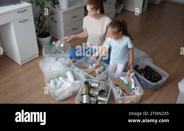 Mother and daughter sorting recyclable items at home. Woman and toddler ...