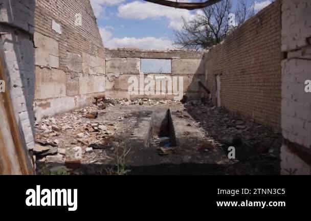 A brick garage without a roof with a broken old gate destroyed by war ...