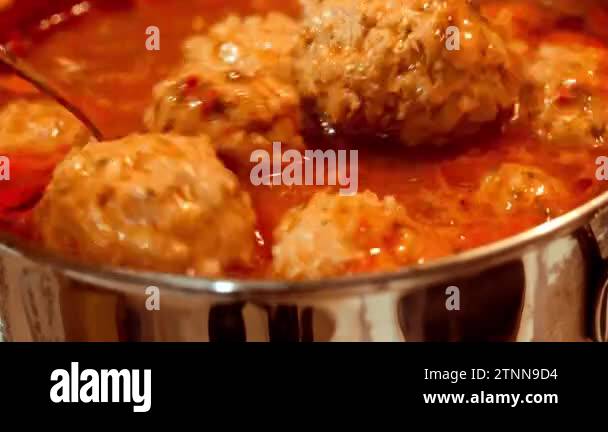 Cooking meat balls in tomato sauce. Close-up, selective focus. A hand ...