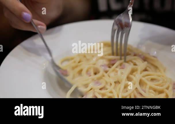 using fork and spoon to eat fresh homemade spaghetti white sauce pasta ...