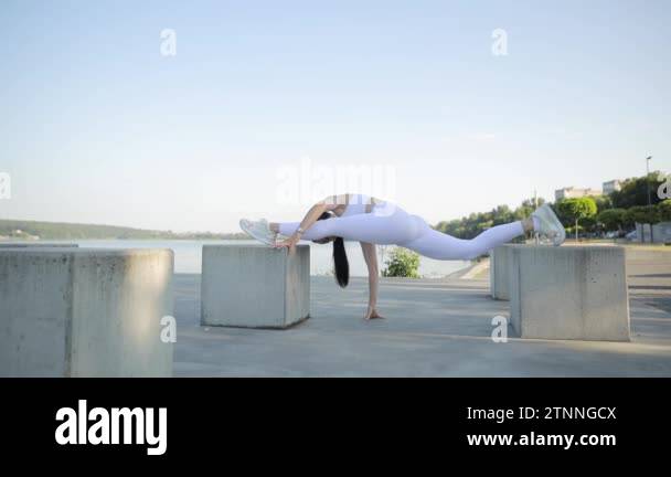 A young girl does split exercises to stretch her legs by straining her ...