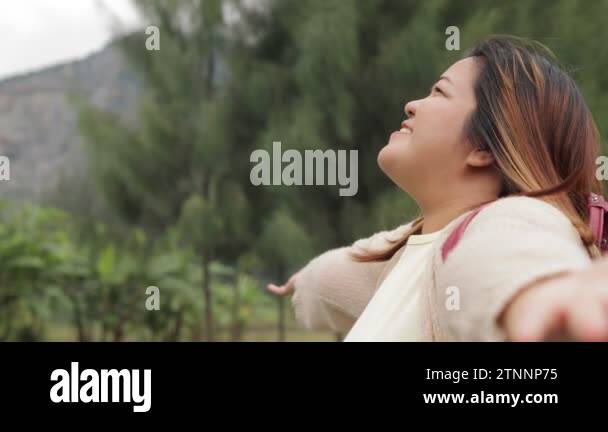 Asian fat woman standing with arms outstretched smiling happily in ...