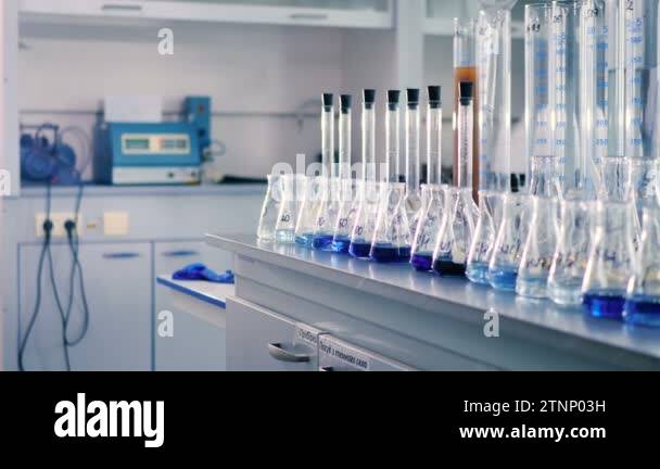 close-up of blue liquor in test tubes with persons in white uniform in ...