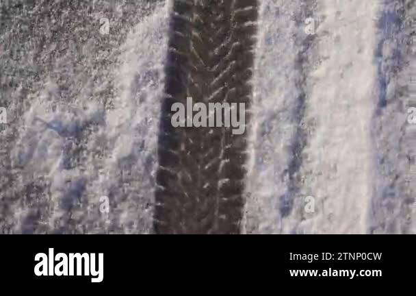 Tire tracks visible on a thin layer of white snow. A cold winter day ...