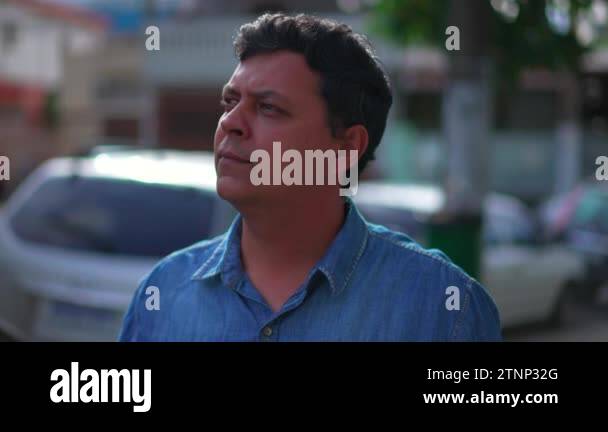 One pensive Brazilian man standing outside in sidewalk with ...